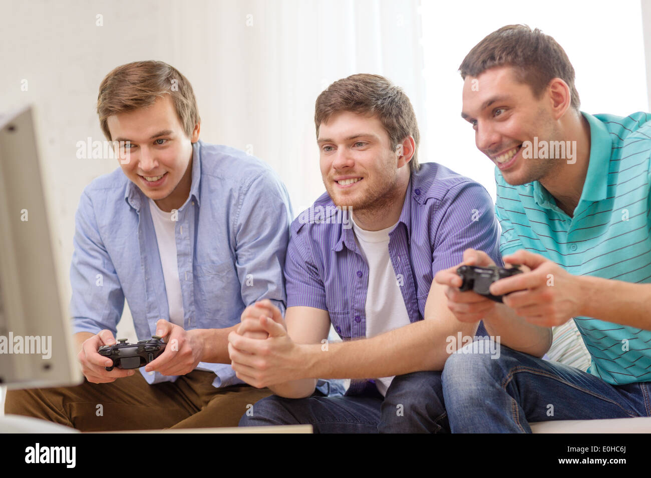 smiling friends playing video games at home Stock Photo - Alamy