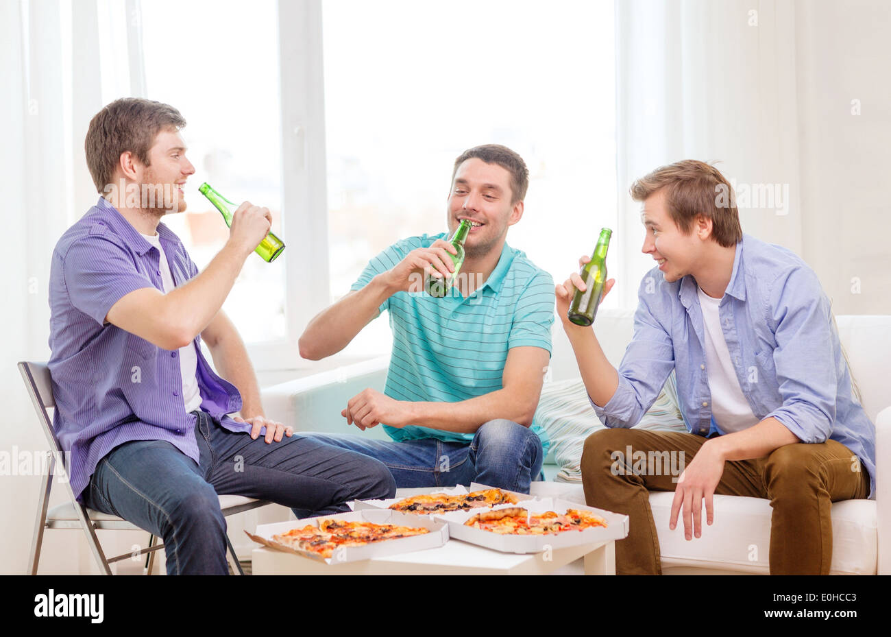 smiling friends with beer and pizza hanging out Stock Photo - Alamy