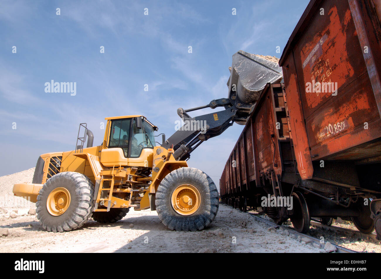 excavator loads gravel into the car of a train Stock Photo - Alamy