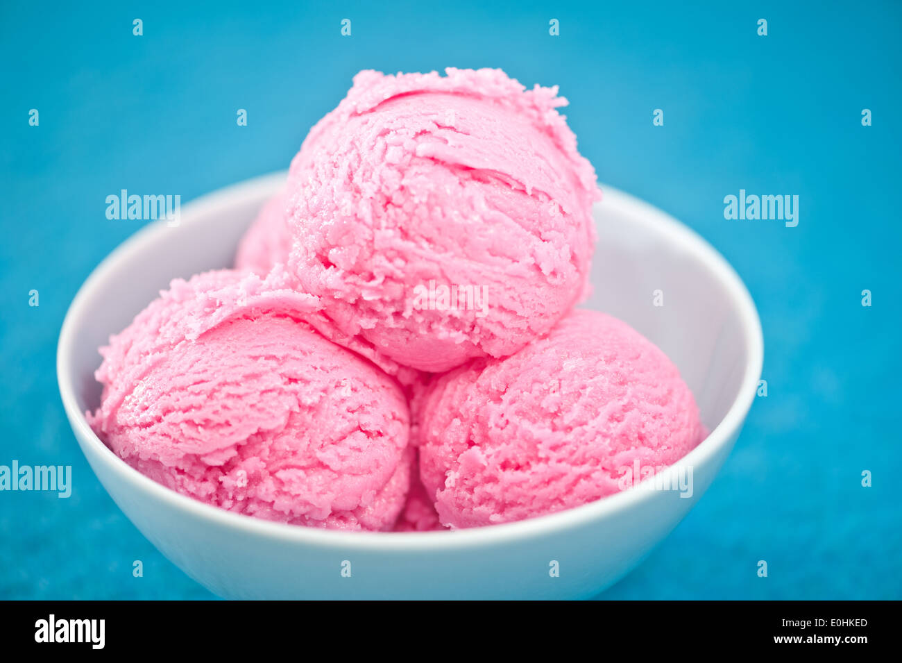 Raspberry ice cream cup over bBLUE background Stock Photo - Alamy
