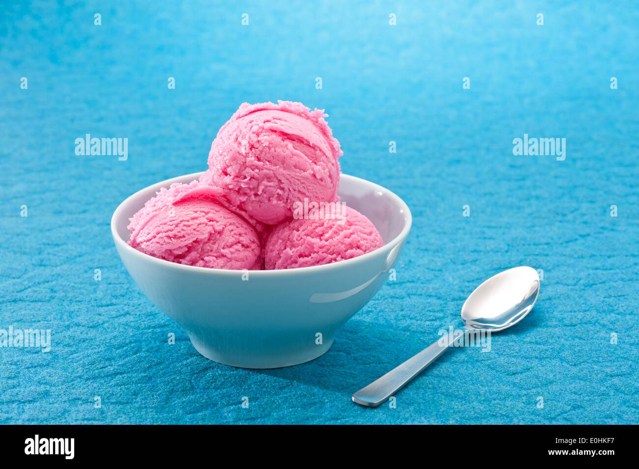 Raspberry ice cream cup over bBLUE background Stock Photo - Alamy