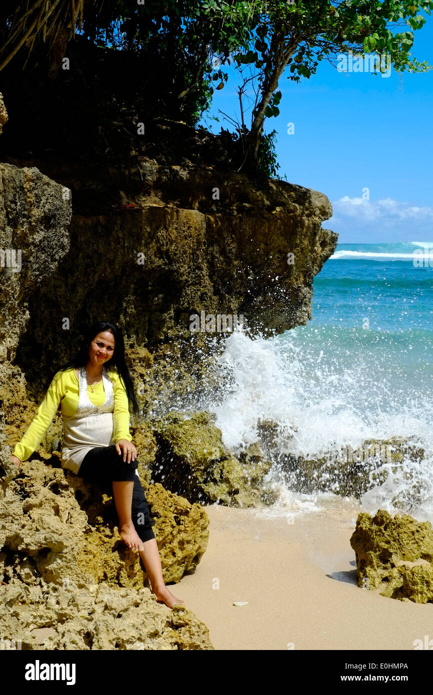 local woman sitting on rocks by the rough sea at balekambang east java ...