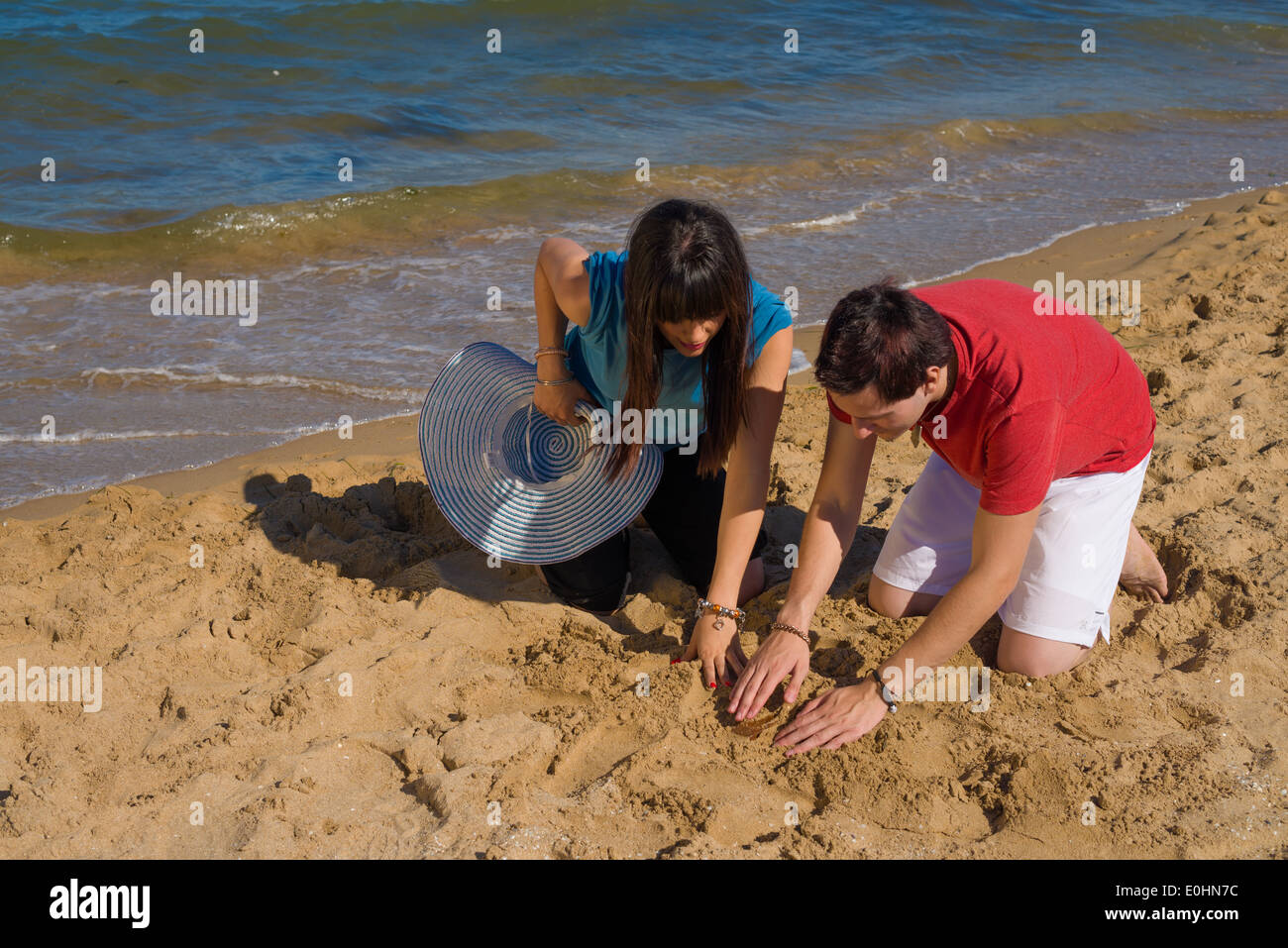 Couple digging on beach sand to find a treasure Stock Photo - Alamy