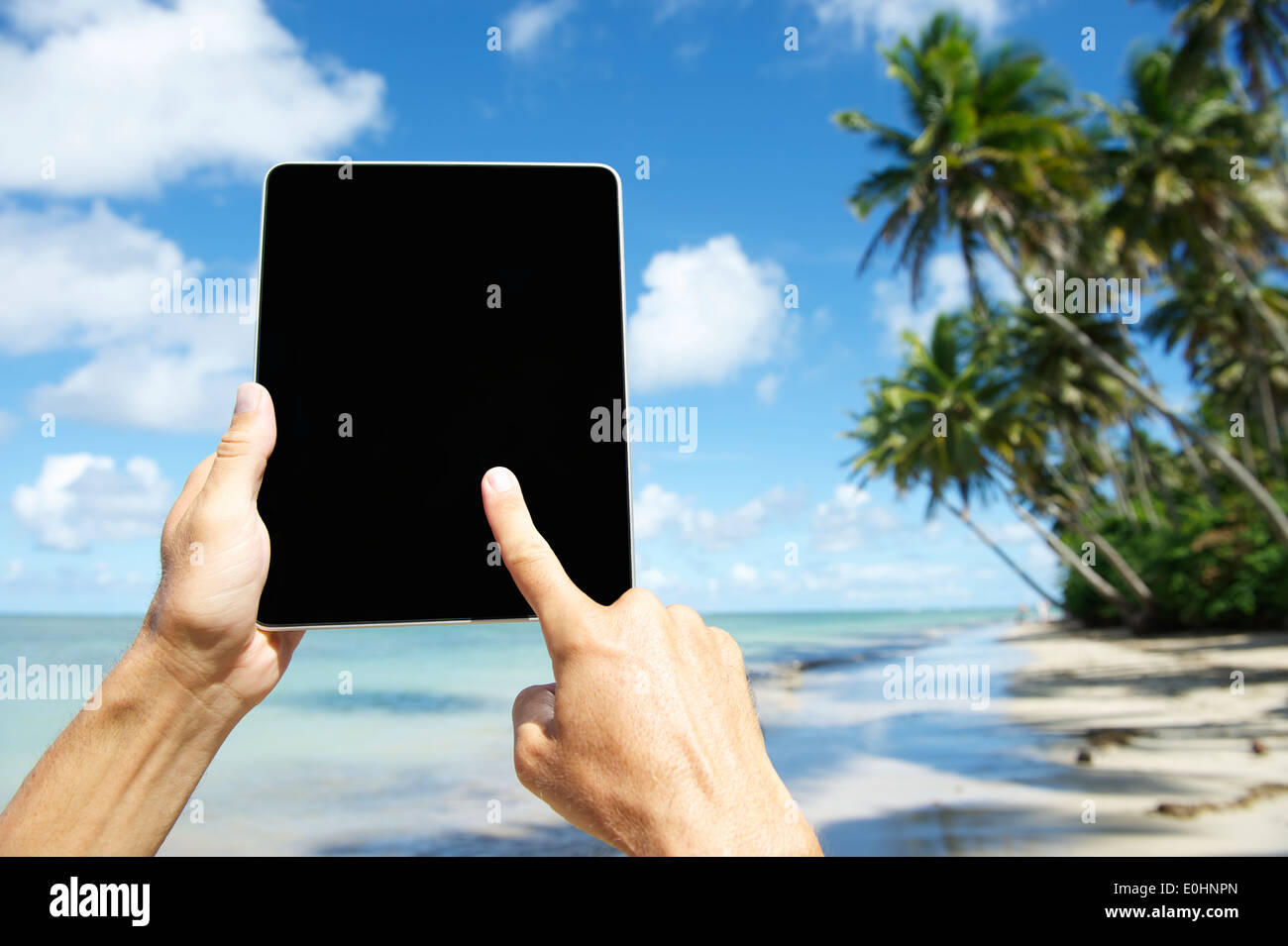 Traveling tourist using touchscreen digital tablet computer at beach in ...