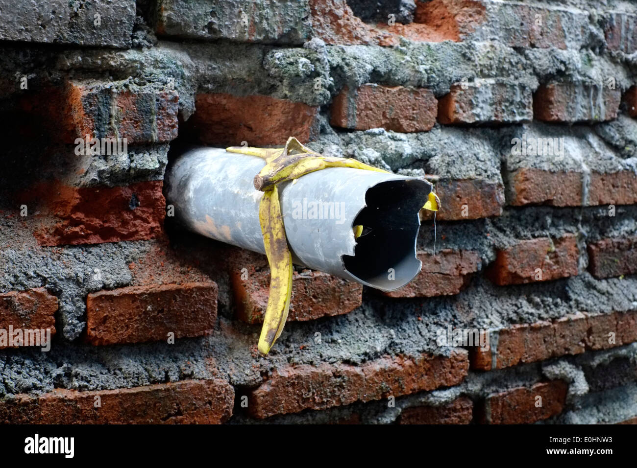 plastic water overflow drainpipe sticking out of wall drains water into ...