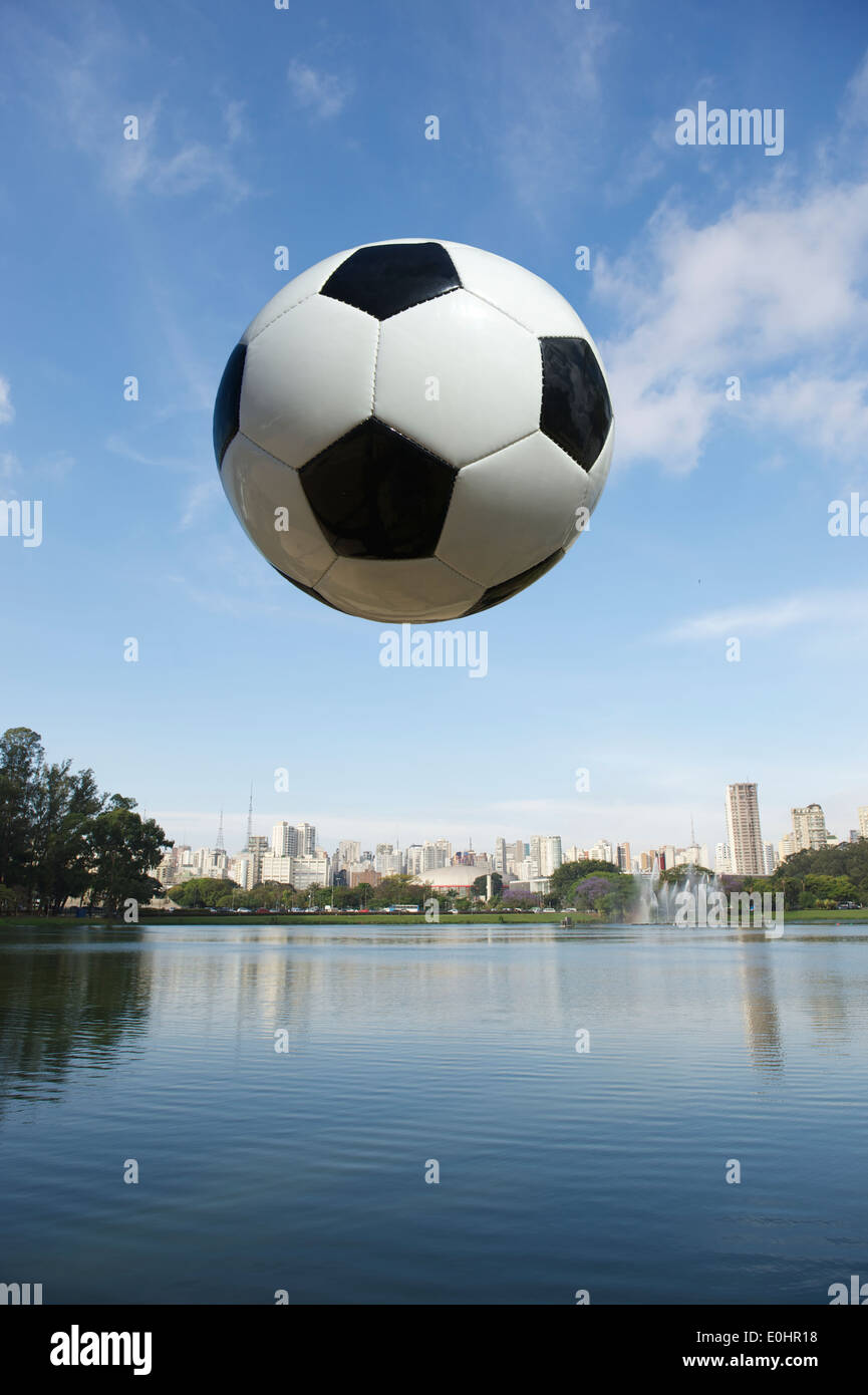 Football soccer ball flying in the sky above tranquil lake in ...