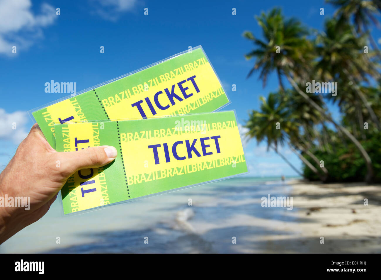 Hand holding pair of Brazil tickets in front of tropical palm trees ...