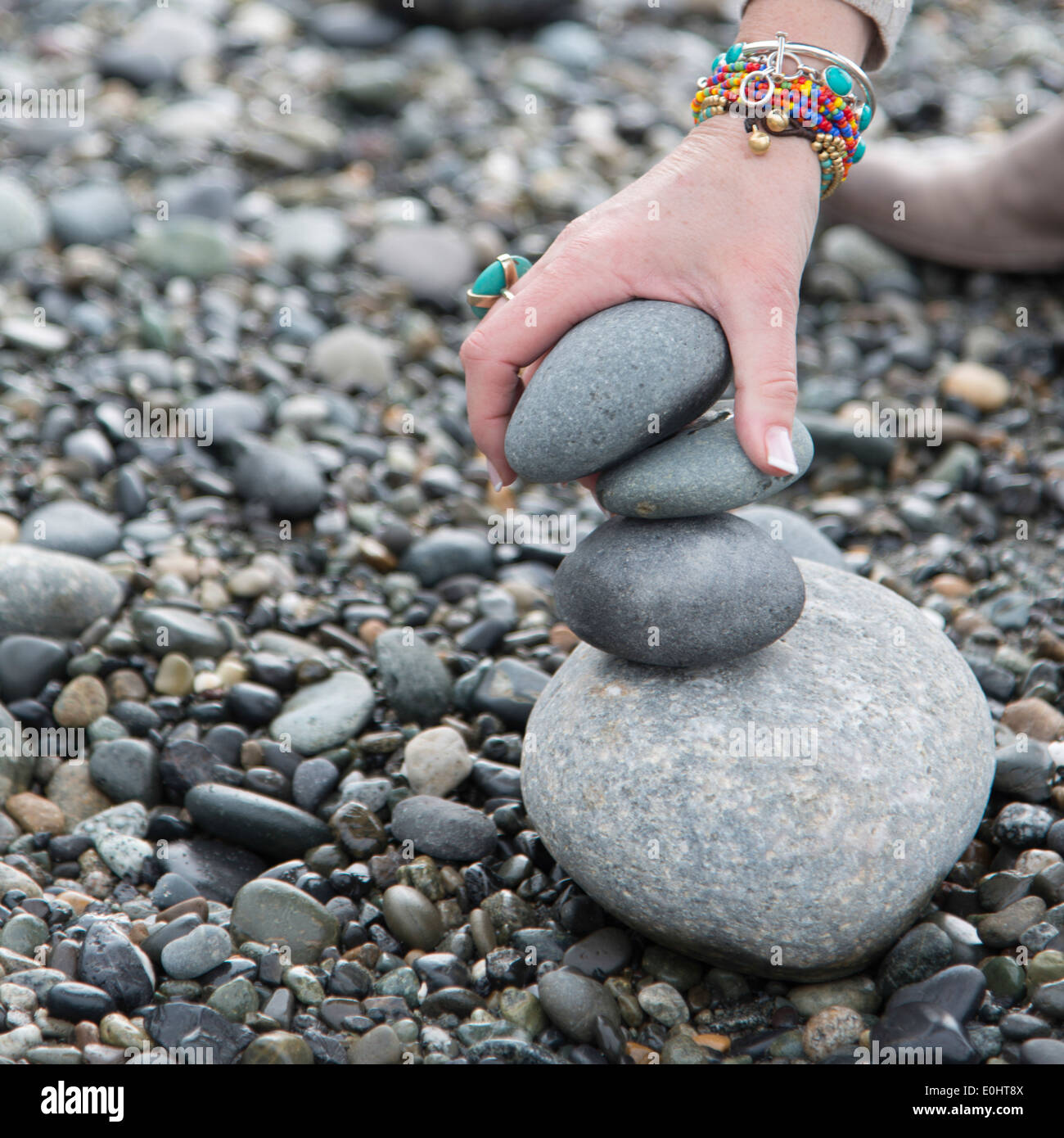 Close-up of a person's hand making stack of stones, Deception Pass ...