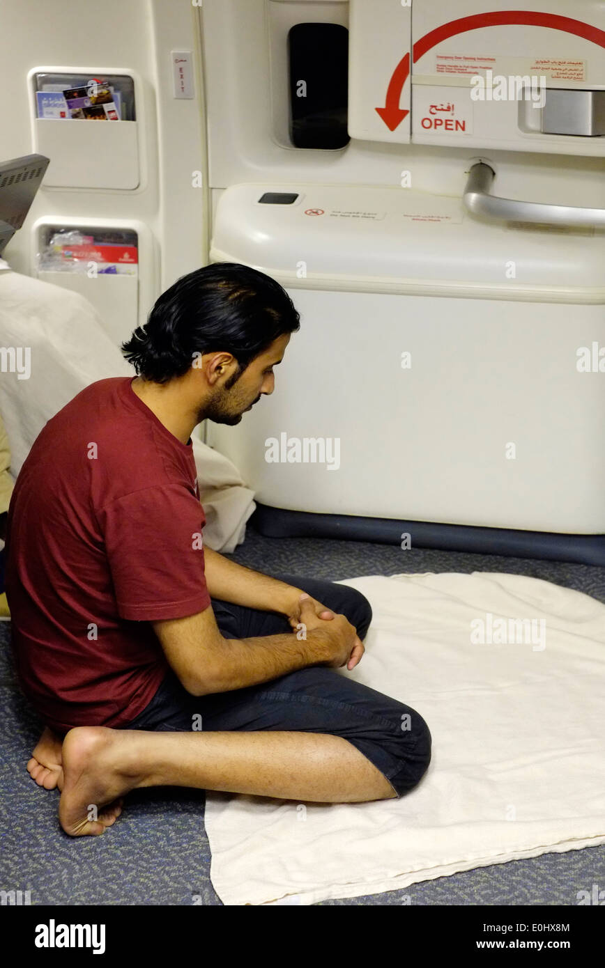 male muslim passenger on board an emirates flight prays towards mecca ...