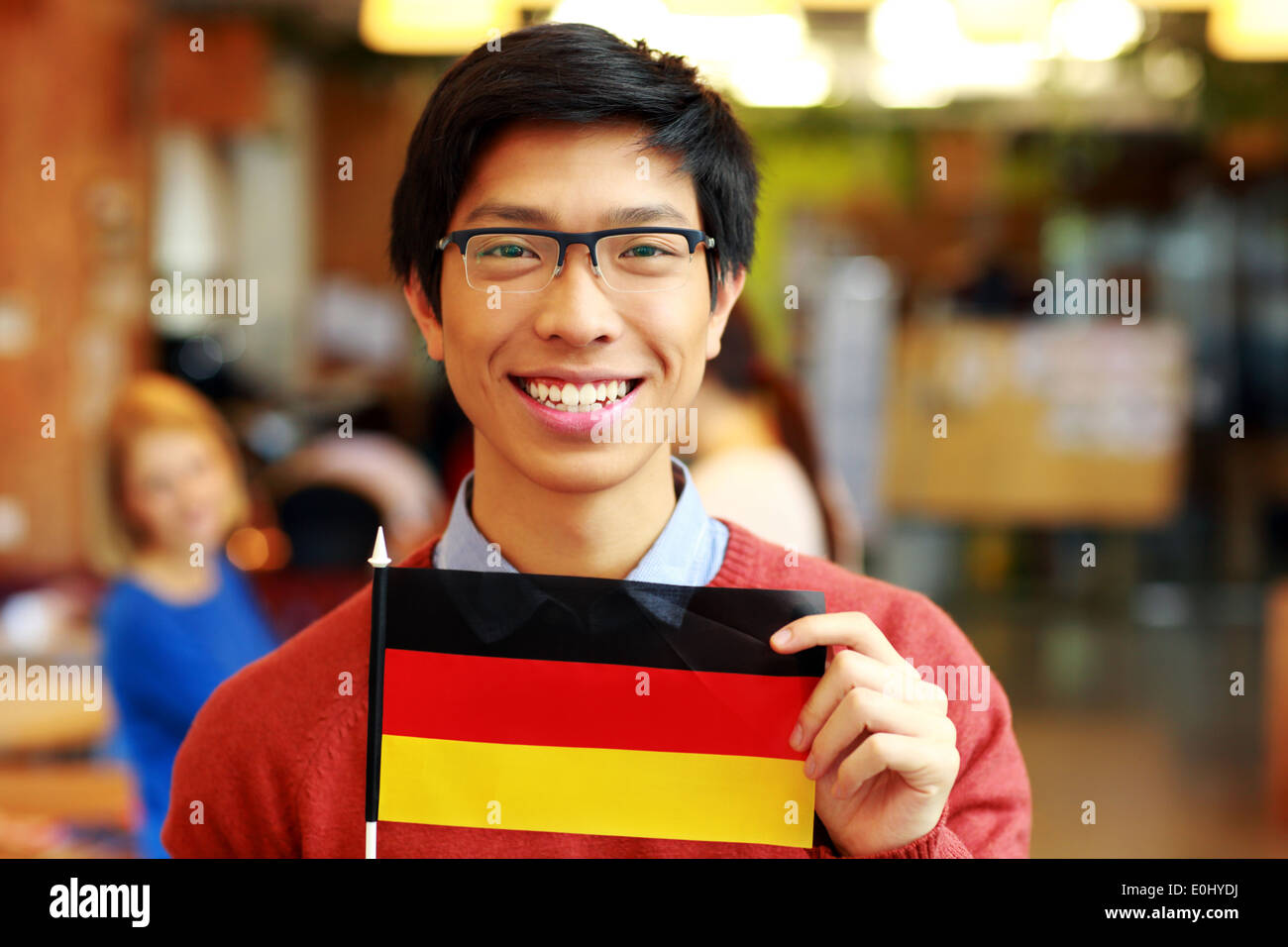 Cheerful asian student holding flag of germany Stock Photo - Alamy