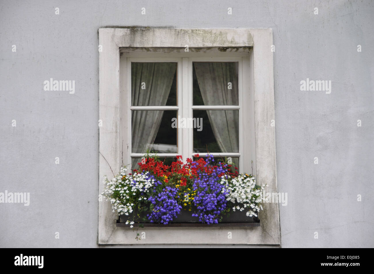A small picturesque window with colourful flowers on the window sill ...