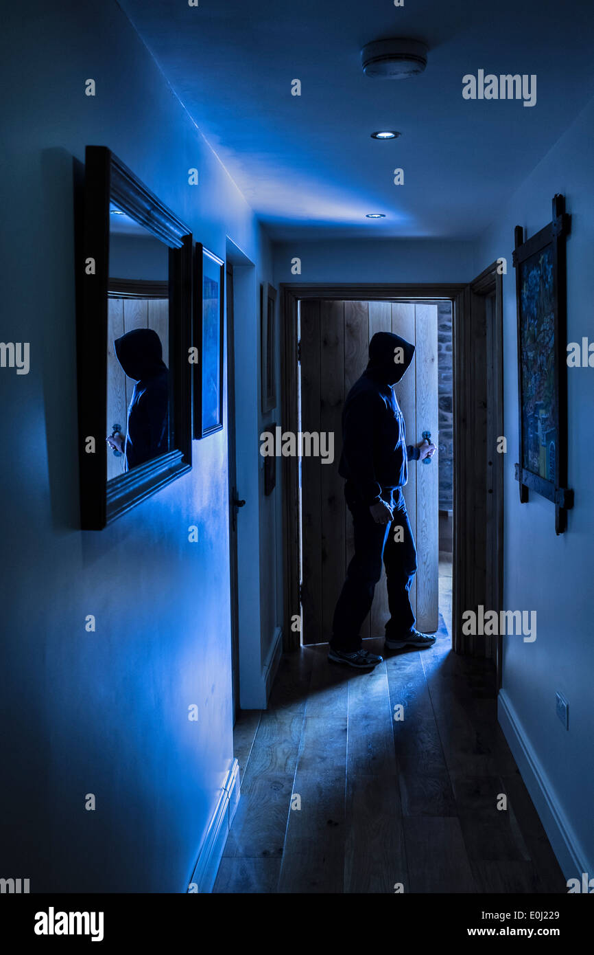 An anonymous hooded male entering a room Stock Photo - Alamy