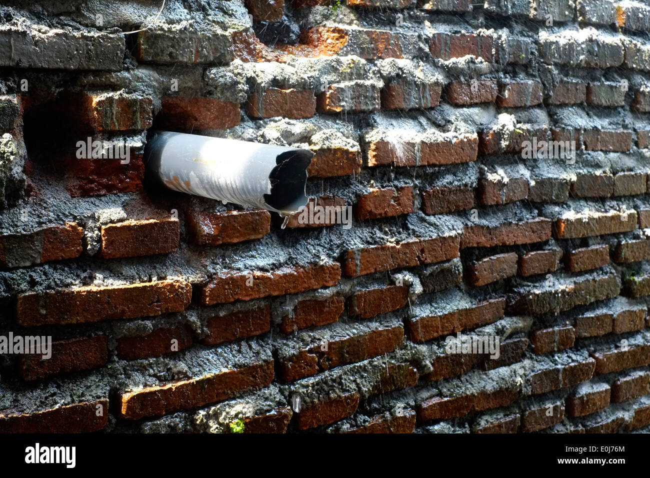 plastic water overflow drainpipe sticking out of wall drains water into ...