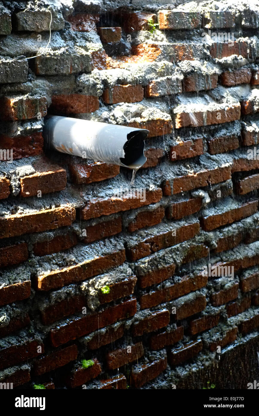 plastic water overflow drainpipe sticking out of wall drains water into ...