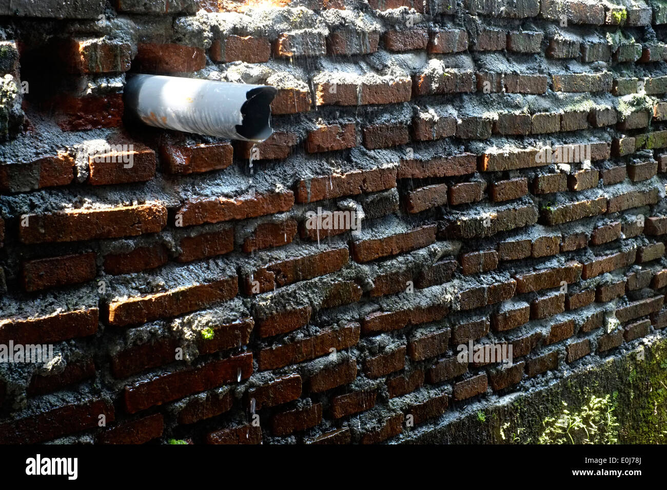 plastic water overflow drainpipe sticking out of wall drains water into ...