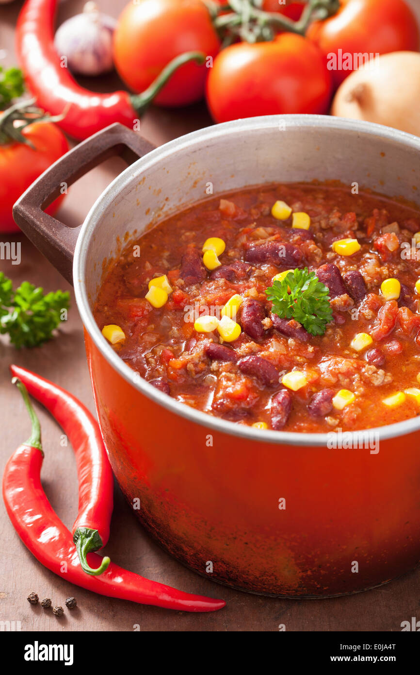 mexican chili con carne in red rustic pot with ingredients Stock Photo ...