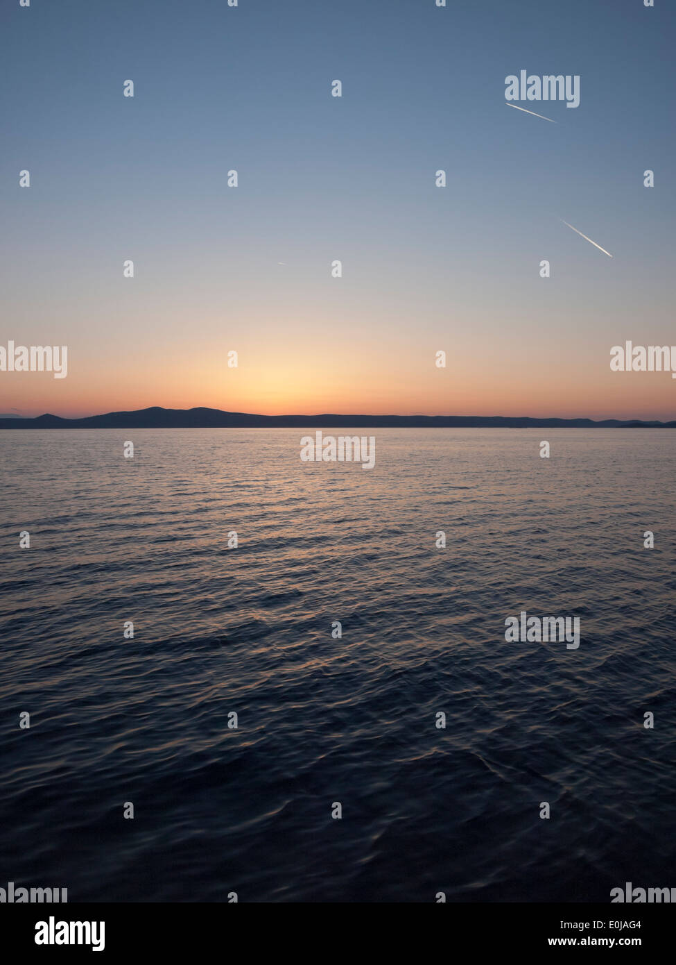 Island coast at sunrise with sky with plane traces Stock Photo - Alamy