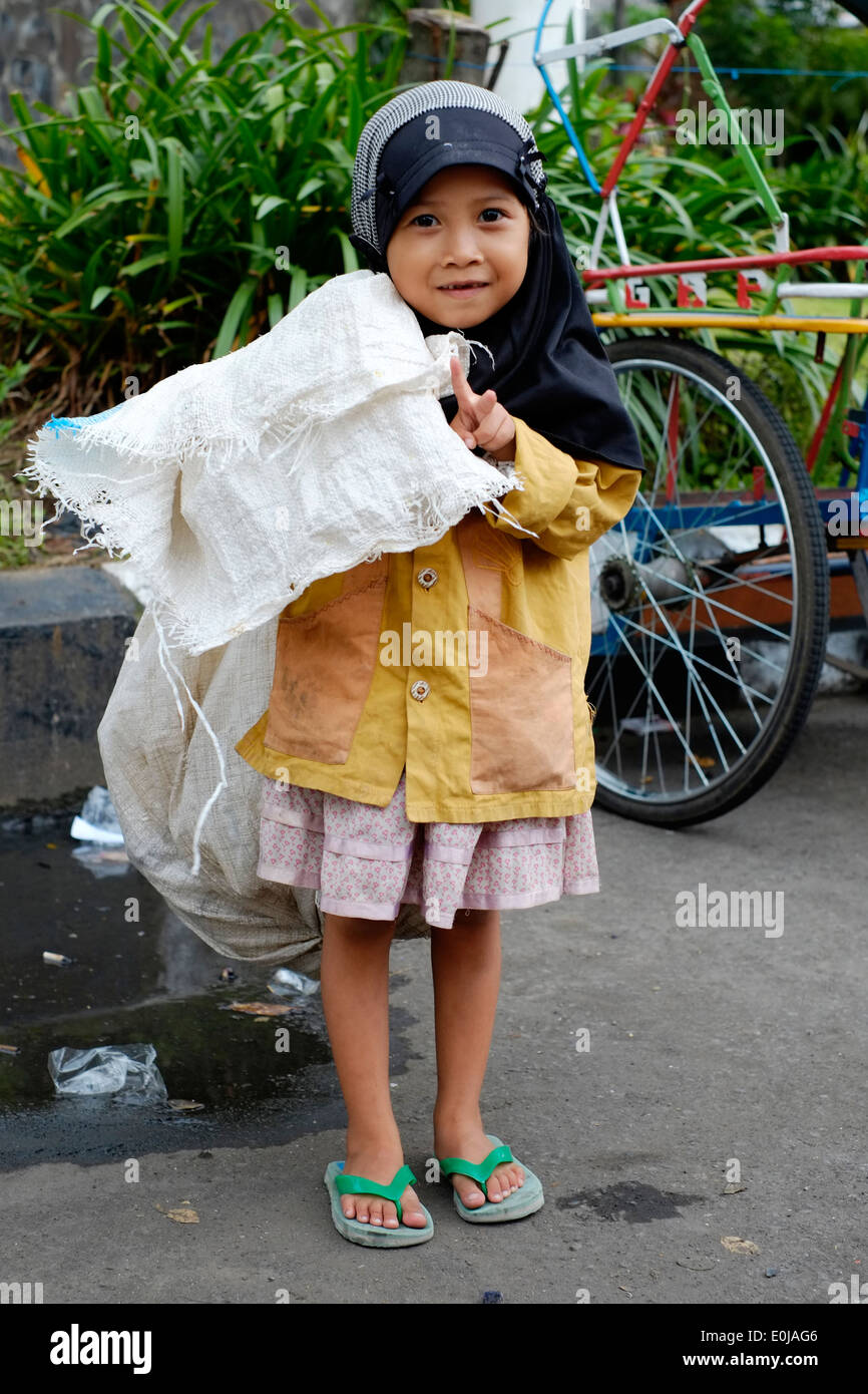 little street girl carrying a huge sack to collect waste plastic to ...