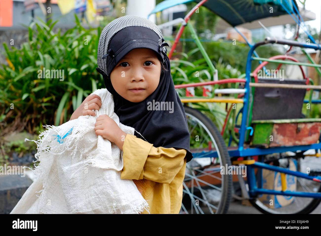 little street girl carrying a huge sack to collect waste plastic to ...