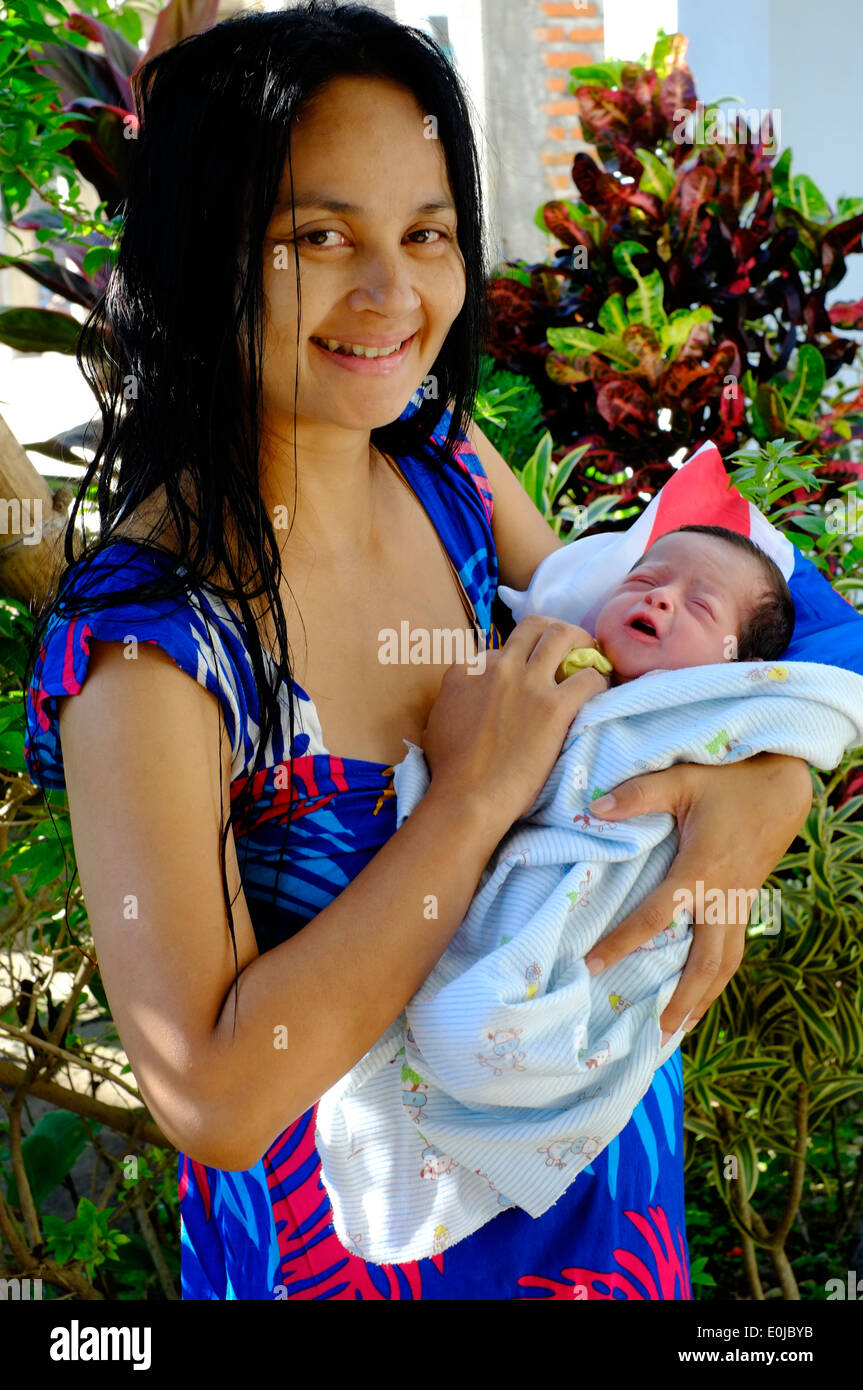 smiling new indonesian mother holds her newborn daughter after bringing ...