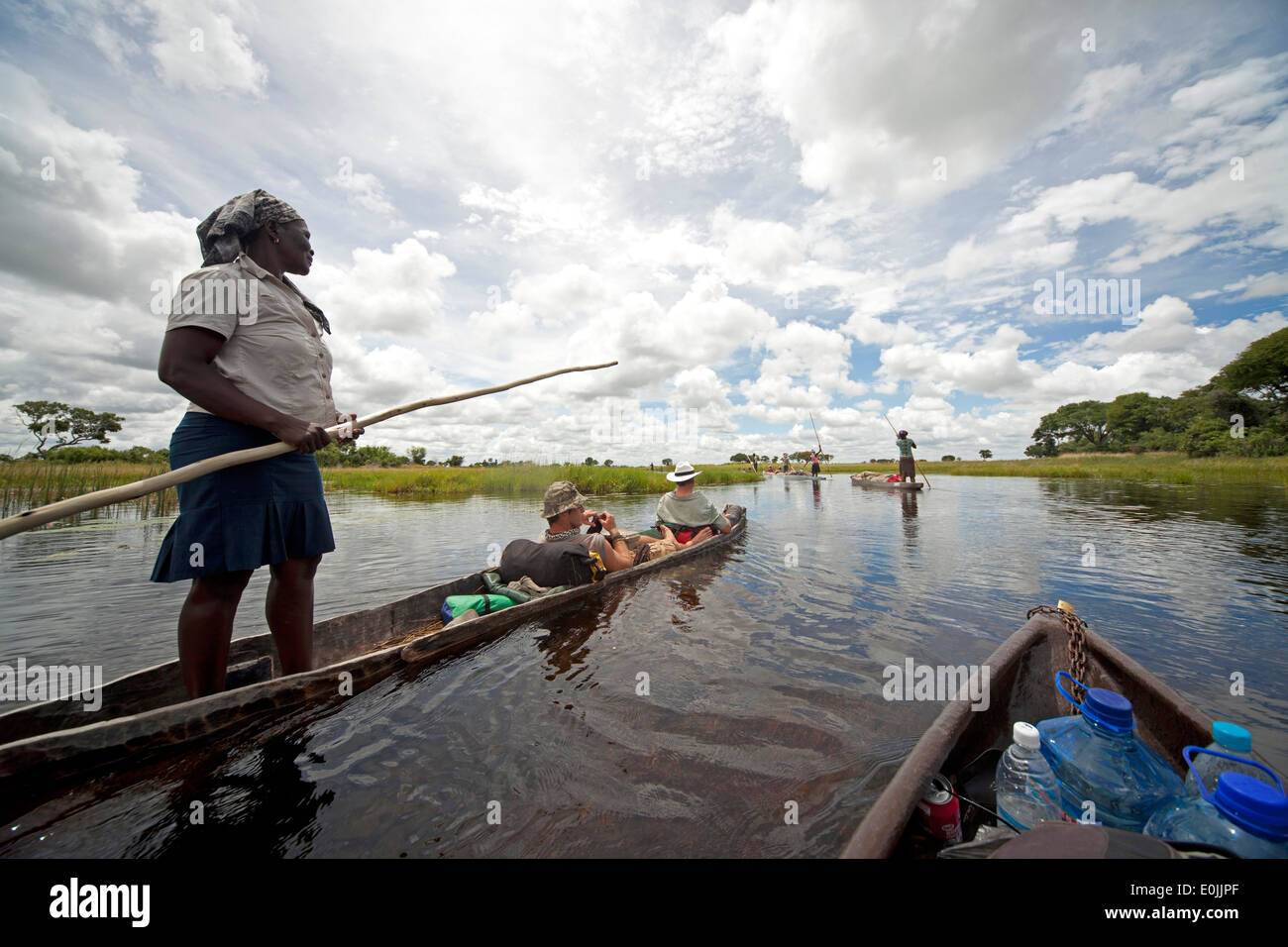 tourists on a traditional mokoro boat in the Okavango Delta, Botswana ...