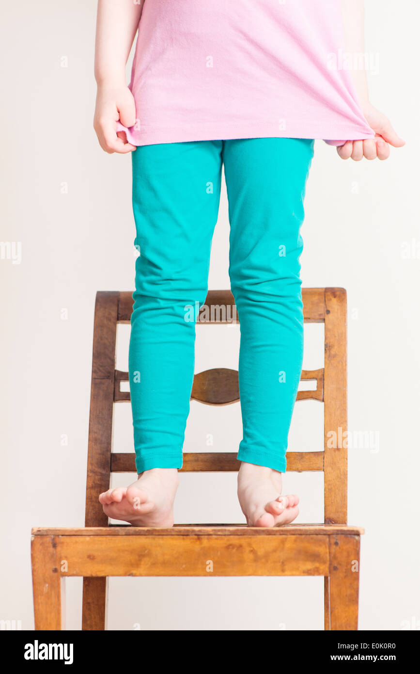 Little girl, 4 years old, standing with bare feet on a small wooden ...