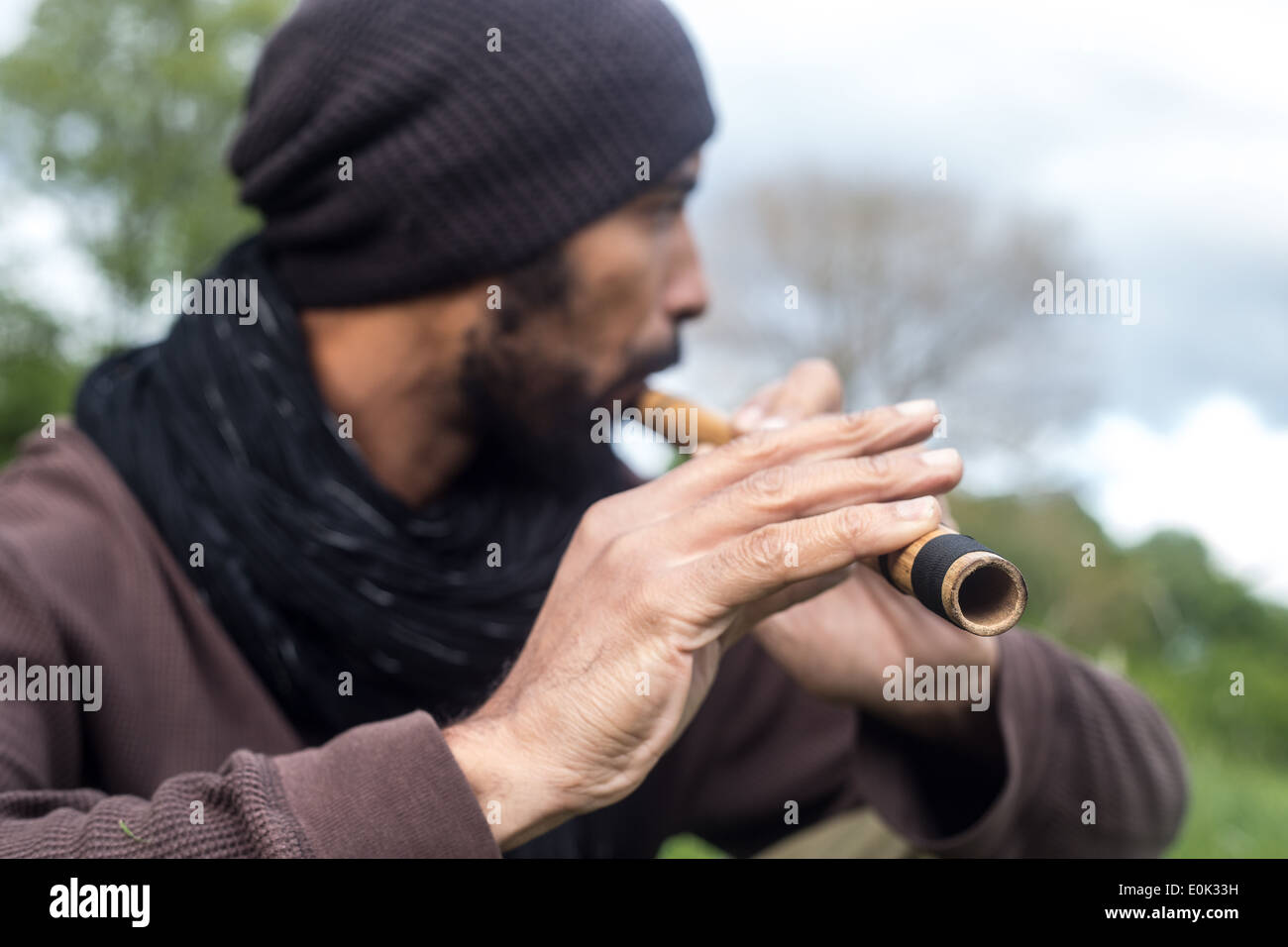 mixed race man playing flute in the long grass on hampstead heath ...