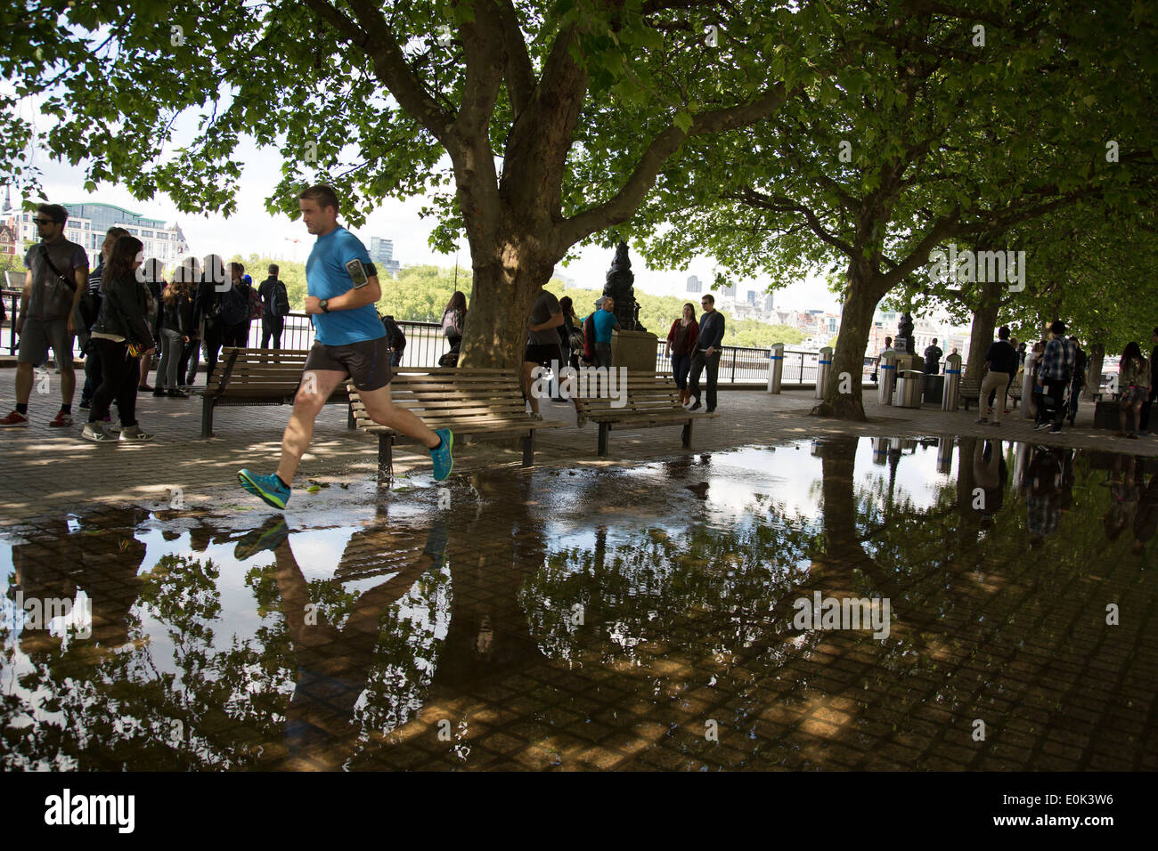Man running through a deep puddle under trees after heavy rain on the ...