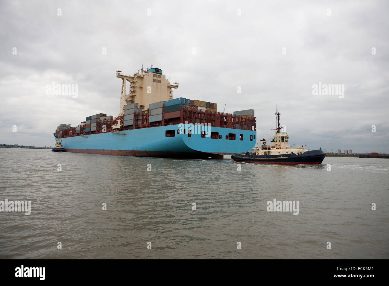 A container ship being escorted to port by tug boats Stock Photo - Alamy