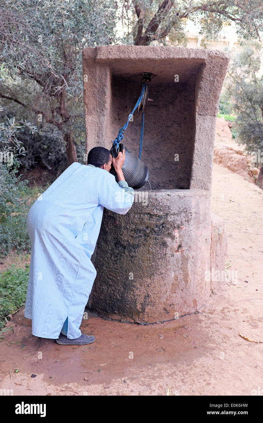 Man in traditional clothes drinking water from the well Stock Photo - Alamy