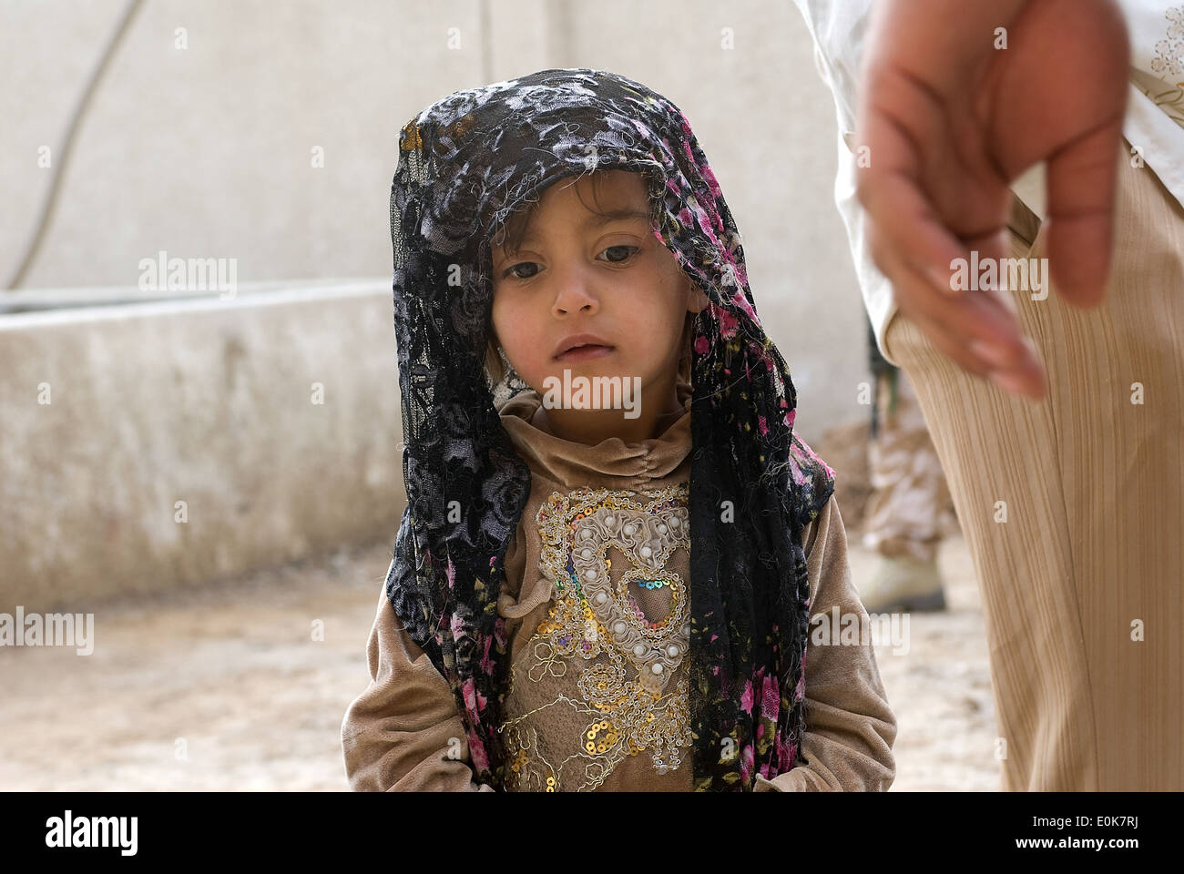 A little Iraqi girl stands by her father's side and observes coalition ...