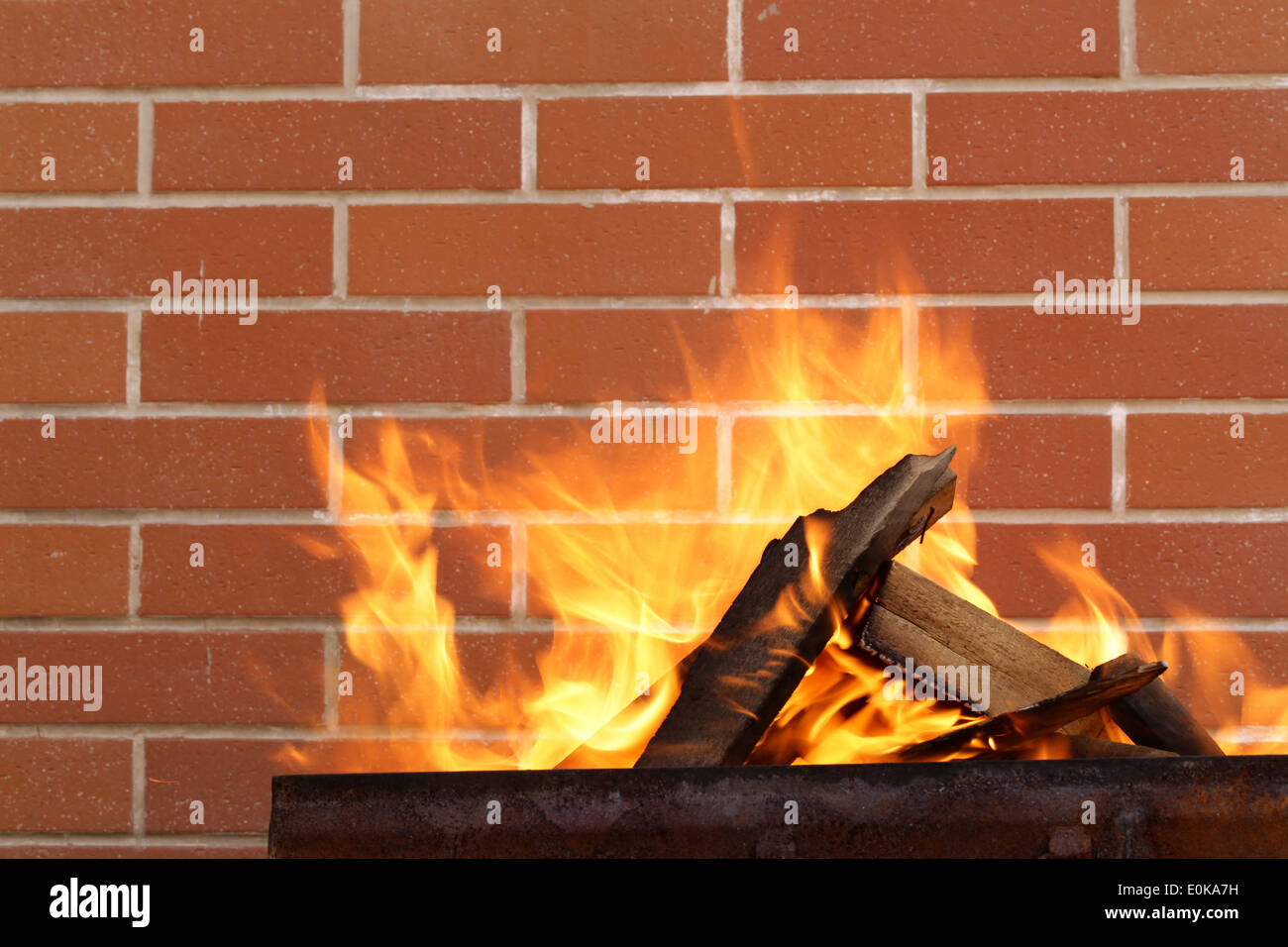 burning wood in a brazier on the brick wall background Stock Photo - Alamy