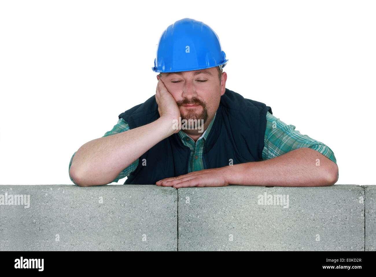Tired builder resting against wall Stock Photo - Alamy