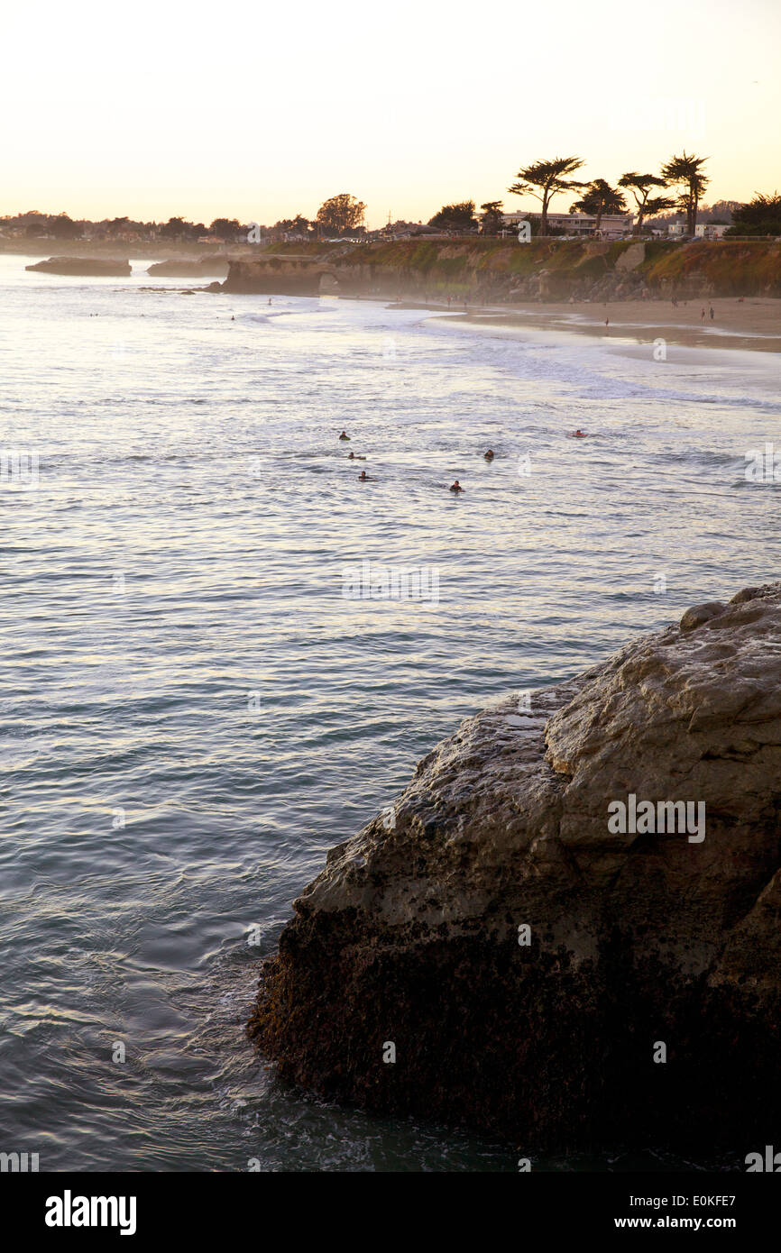 A group of surfers off in the distance waits patiently for the next ...