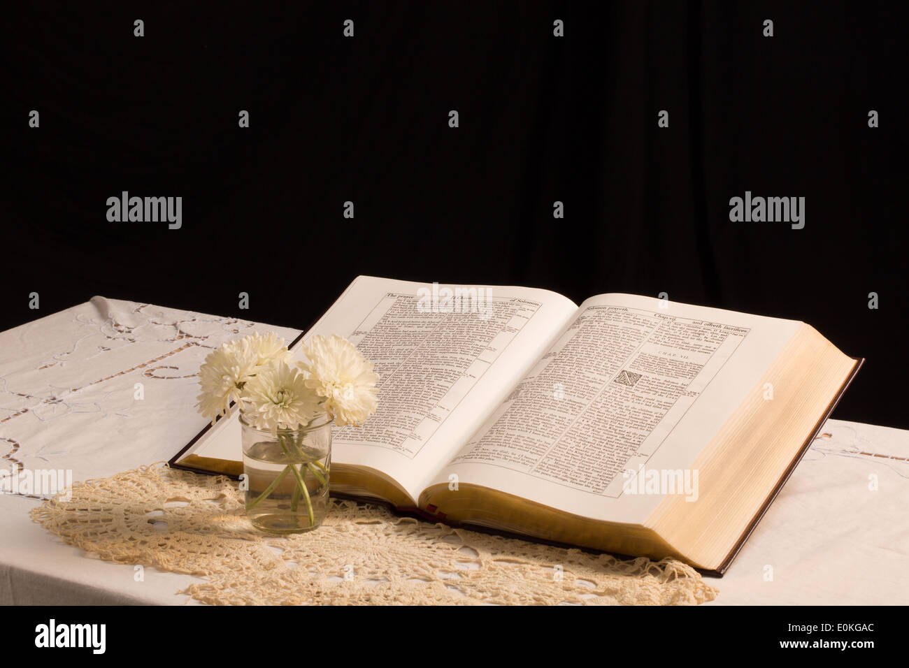 Jar of flowers next to an open Bible Stock Photo - Alamy