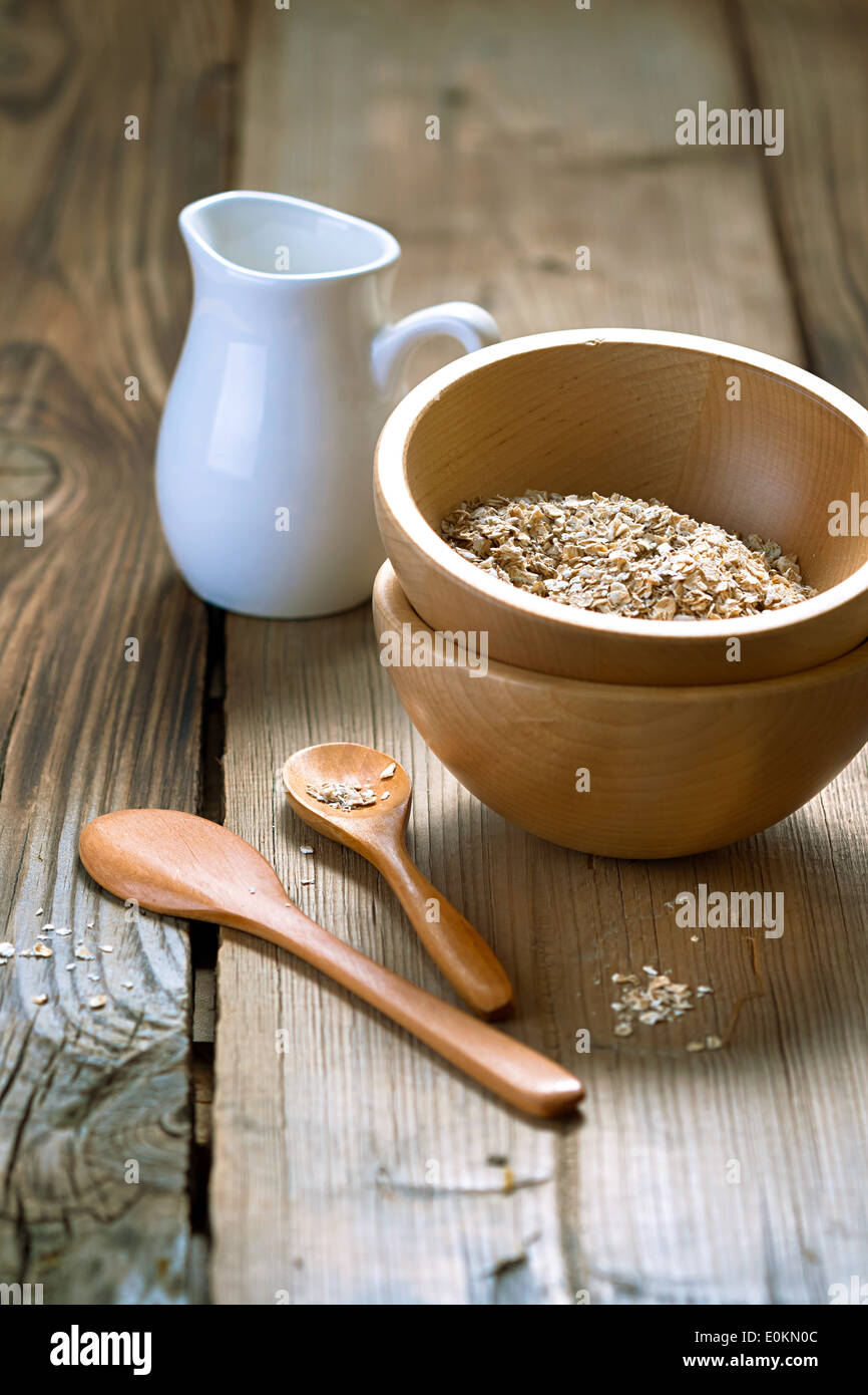 Jug with milk and a wooden bowl with oat groats Stock Photo - Alamy
