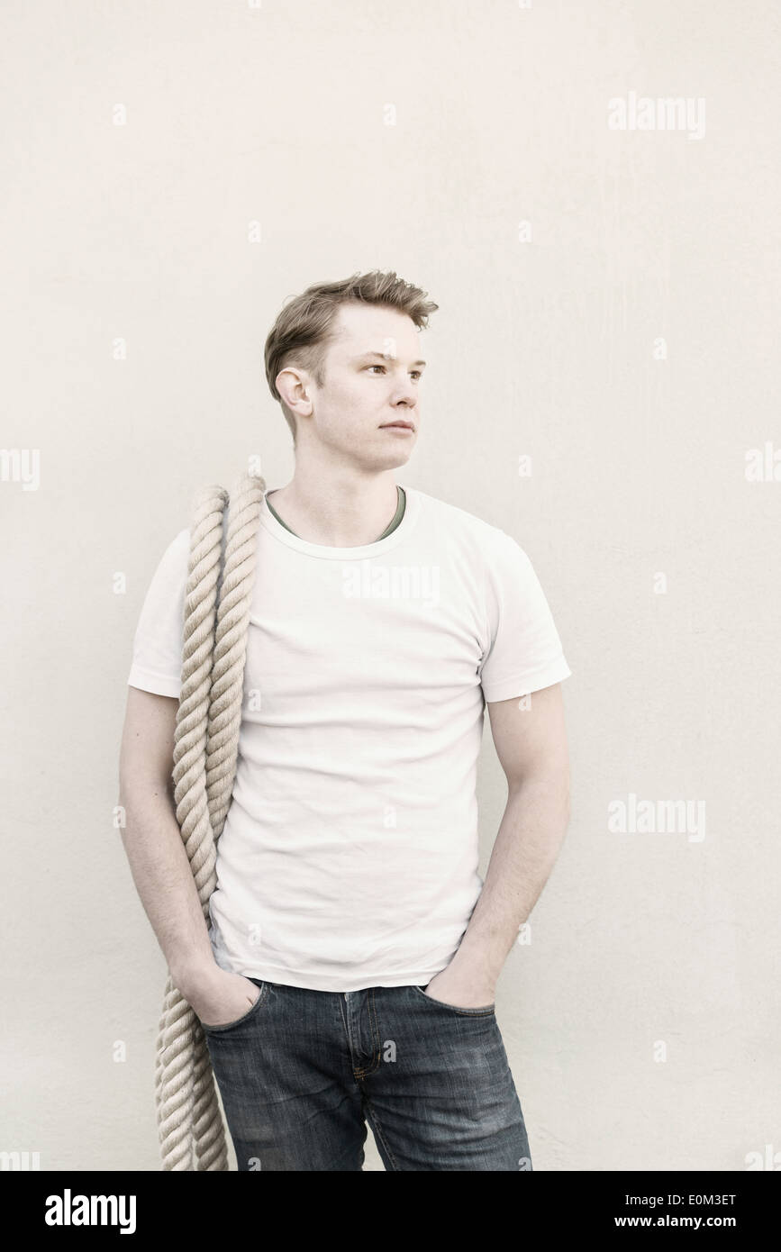 Portrait of young man with a rope. Pensive expression and looking away ...