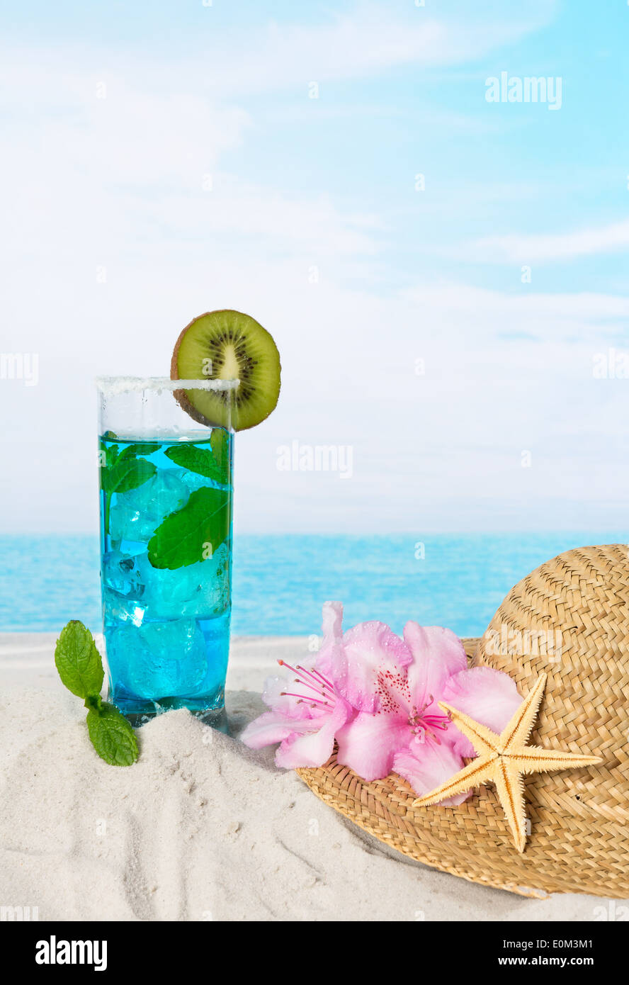 Blue cocktail on the beach with a sunhat and sea shells Stock Photo - Alamy