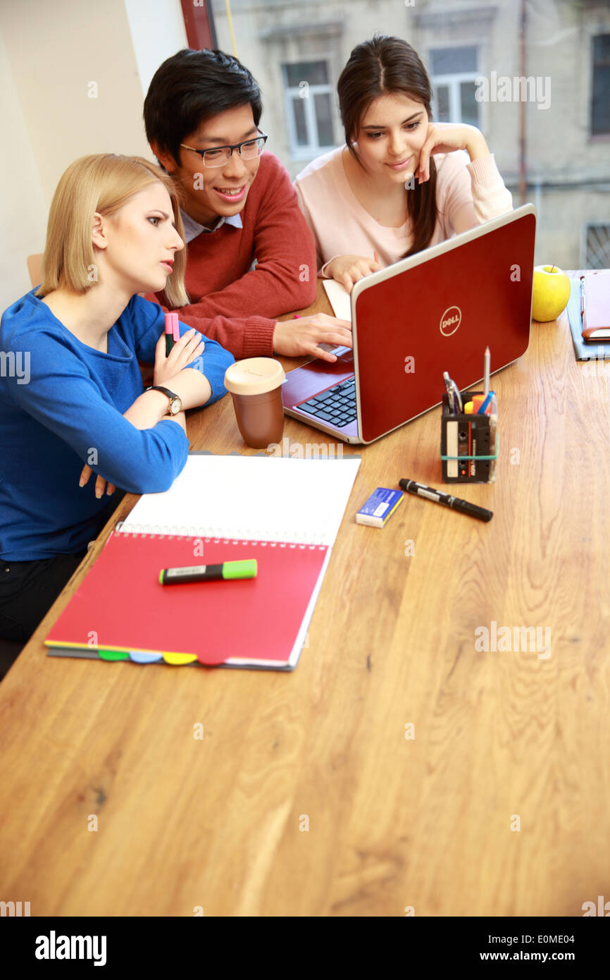 Smiling friends using laptop together Stock Photo - Alamy