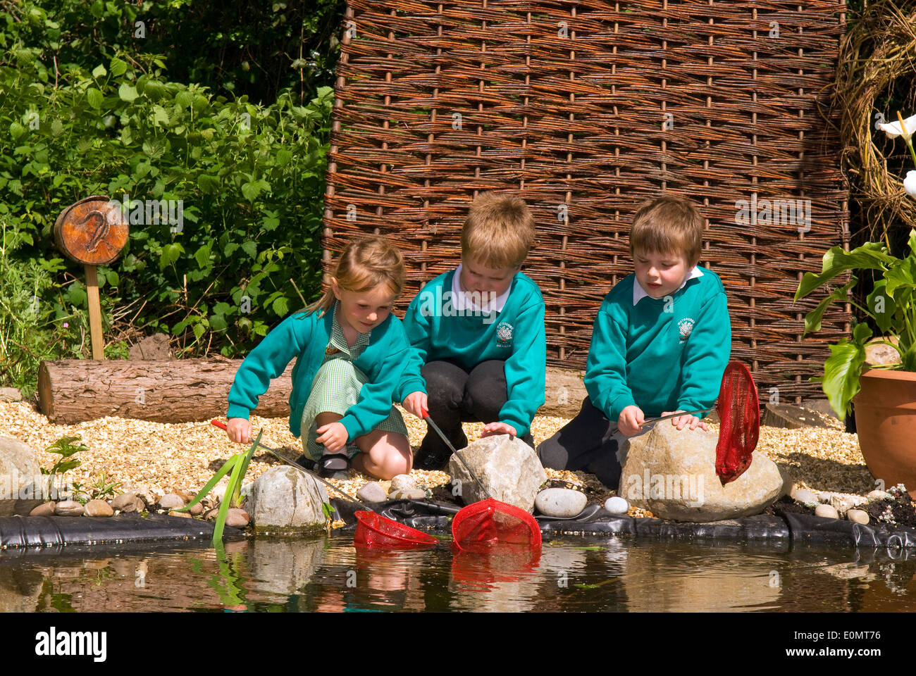Infant school pupils fishing in pond at the school's new nature reserve ...