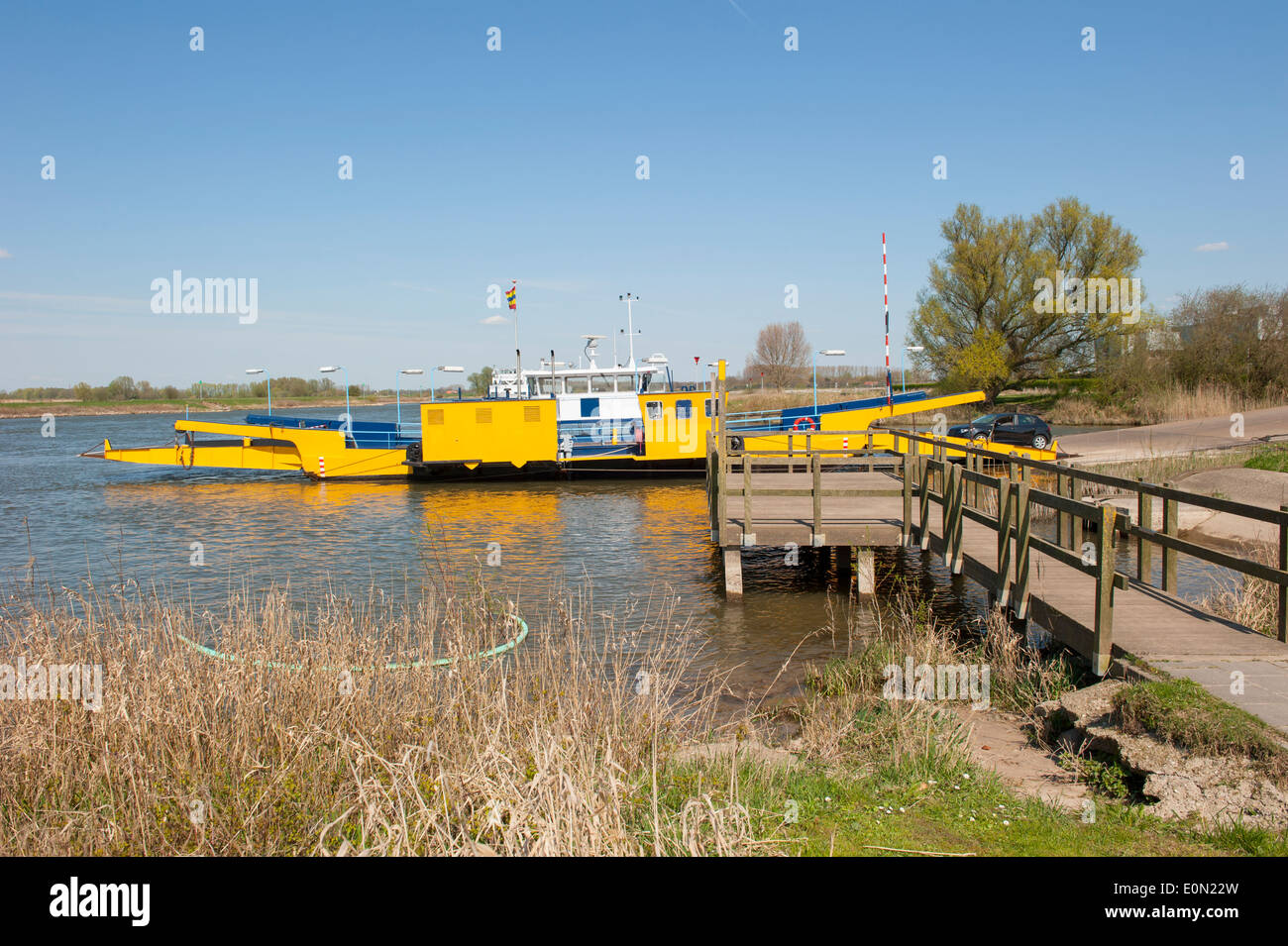 Yellow ferry in river landscape docked at landing stage on levee Stock ...