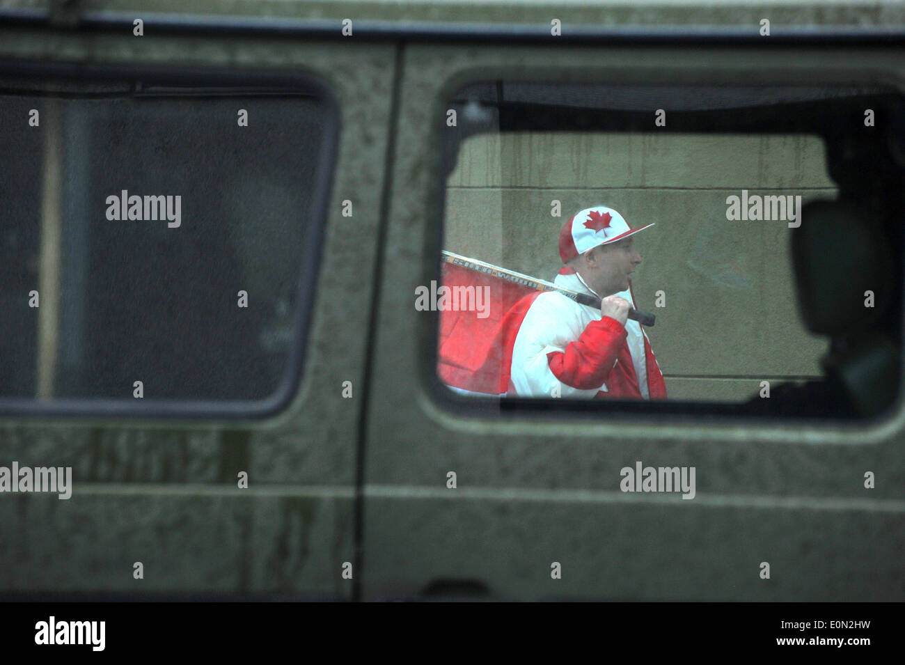 A Canadian Man waving a Canadian flag seen through a military vehicle ...