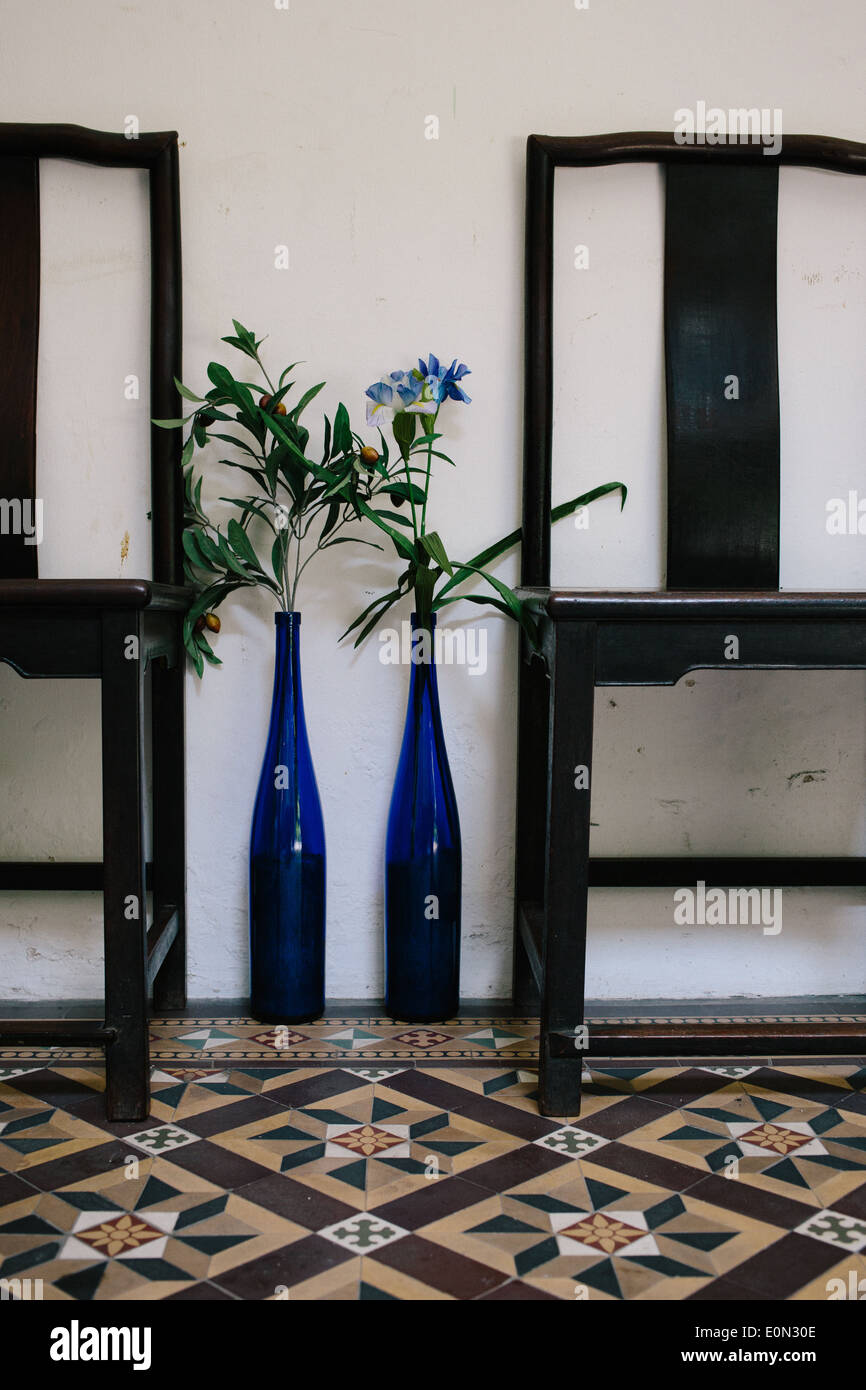 Two blue vases in between two historic wood chairs on patterned floor ...