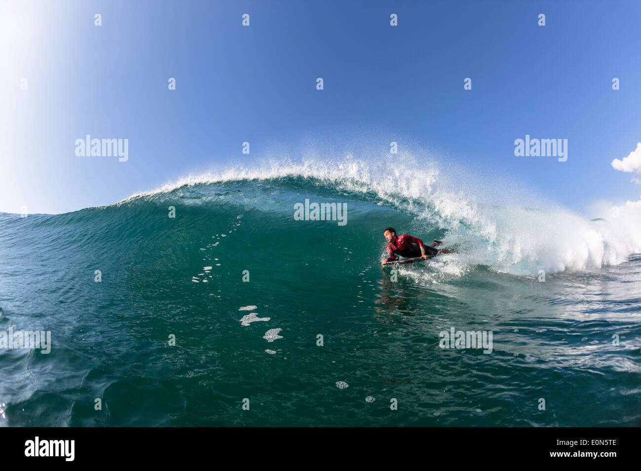 Surfing body-boarder rides hollow ocean blue wave tube, a swimming ...
