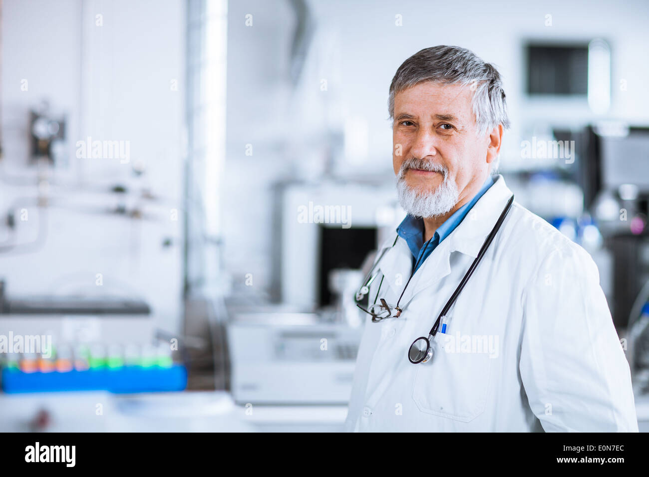 Senior doctor using his tablet computer at work (color toned image ...