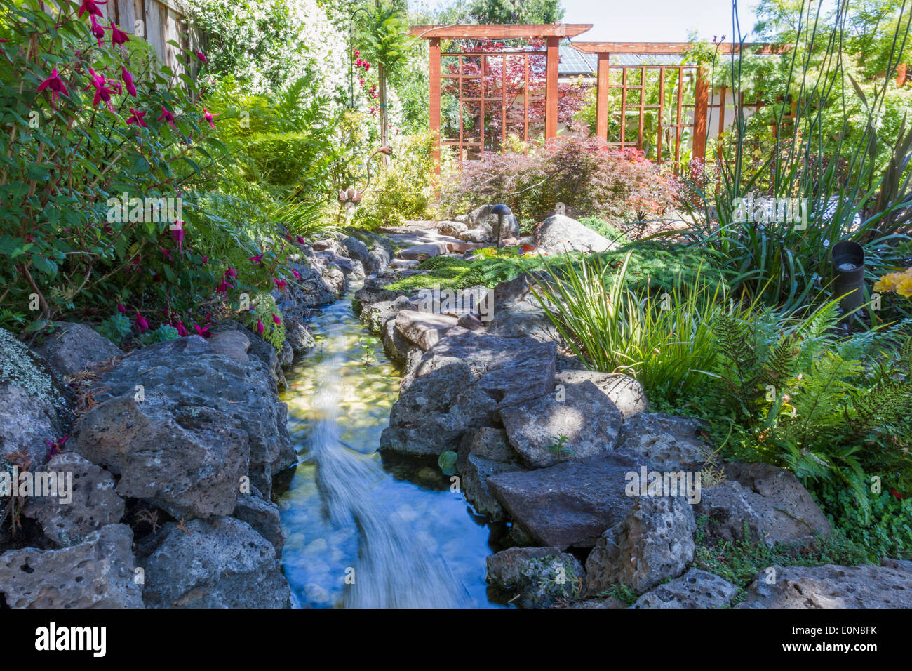 Water from stream flowing between rocks of a beautiful water feature in ...