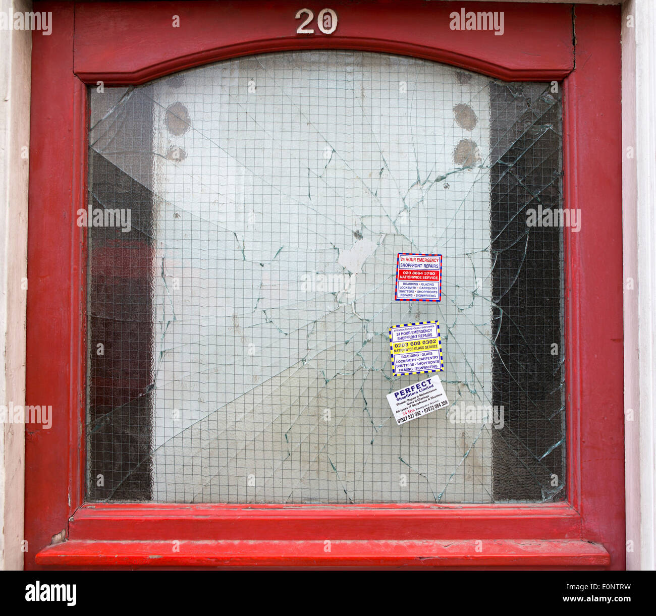 Broken shop door window with advertising stickers from several 24 Hour ...