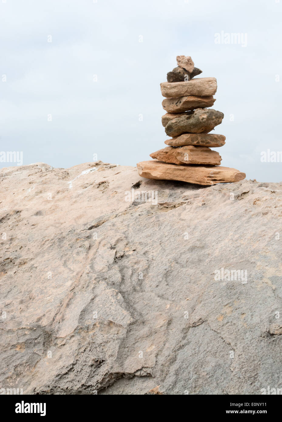 Small cairn, tower of rocks on a limestone cliff by Cap de Ses Salines ...