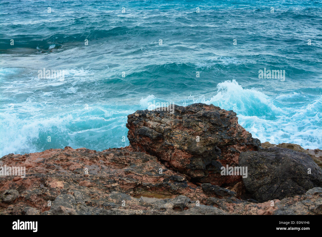 Earthy red limestone rock contrasting with Mediterranean azure blue ...