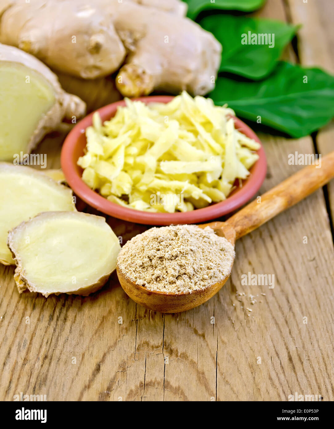 Brown dish with grated ginger, a wooden spoon with powder, ginger root ...